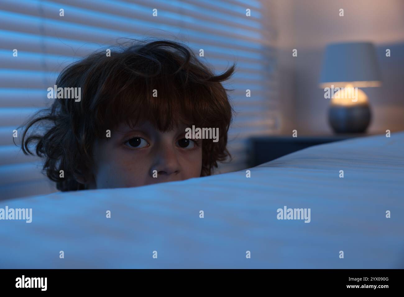 Scared boy hiding behind bed at night. Space for text Stock Photo - Alamy