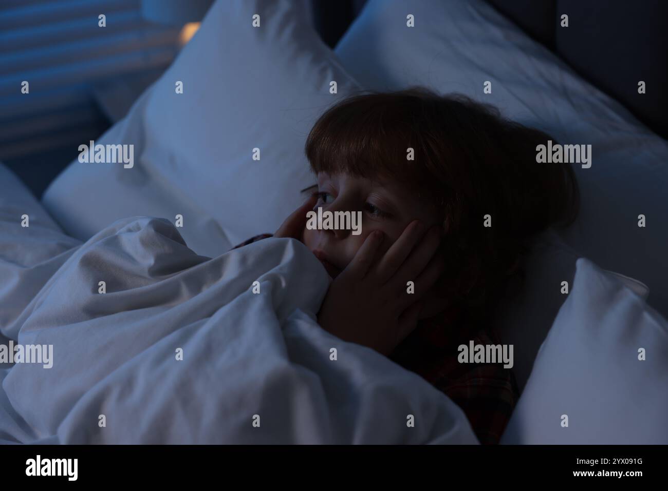 Scared boy lying in bed at night Stock Photo - Alamy