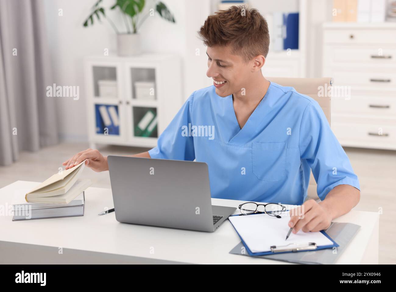 Medical student in uniform studying at table indoors Stock Photo - Alamy