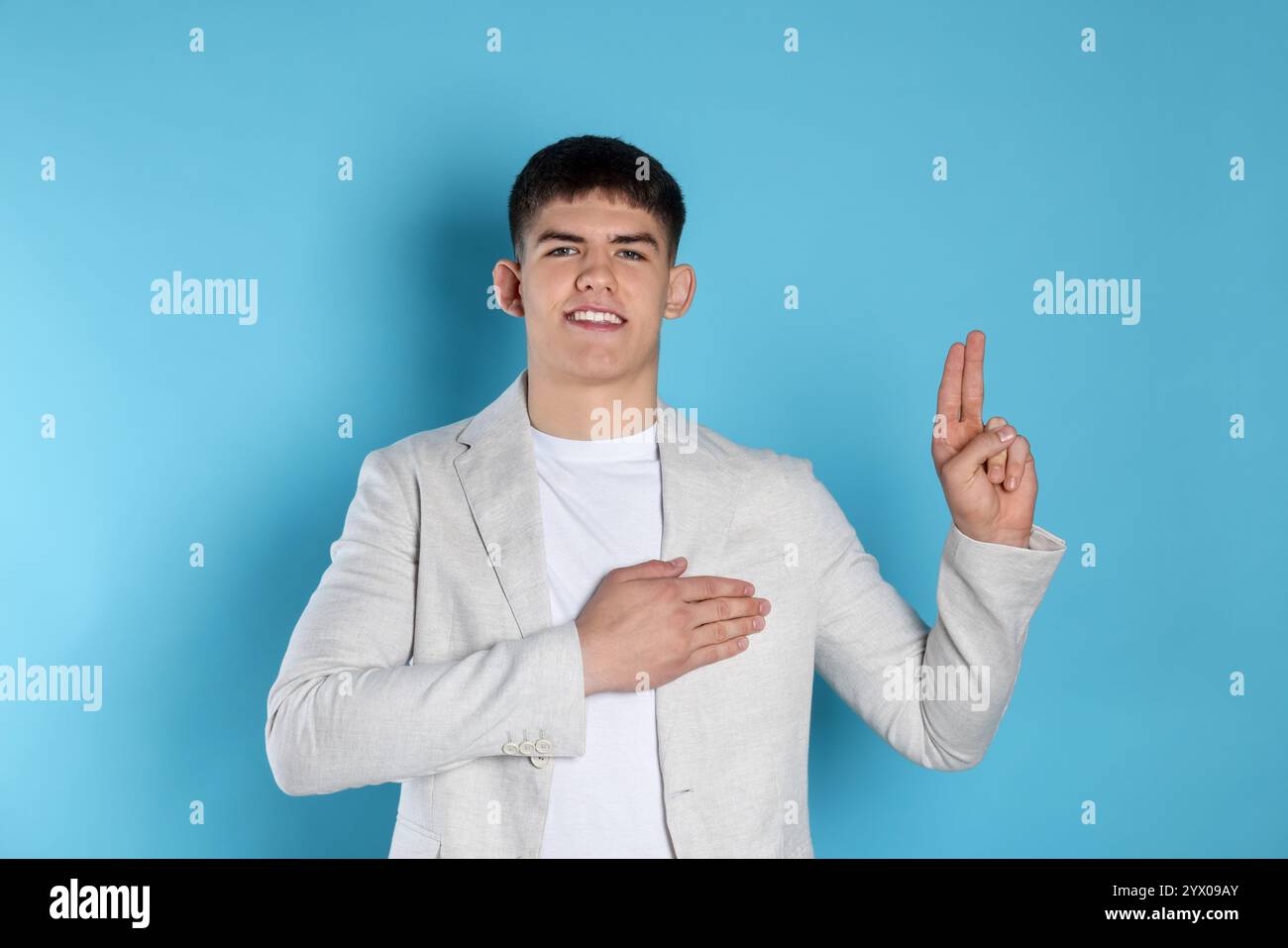 Man showing oath gesture on light blue background. Making promise Stock ...