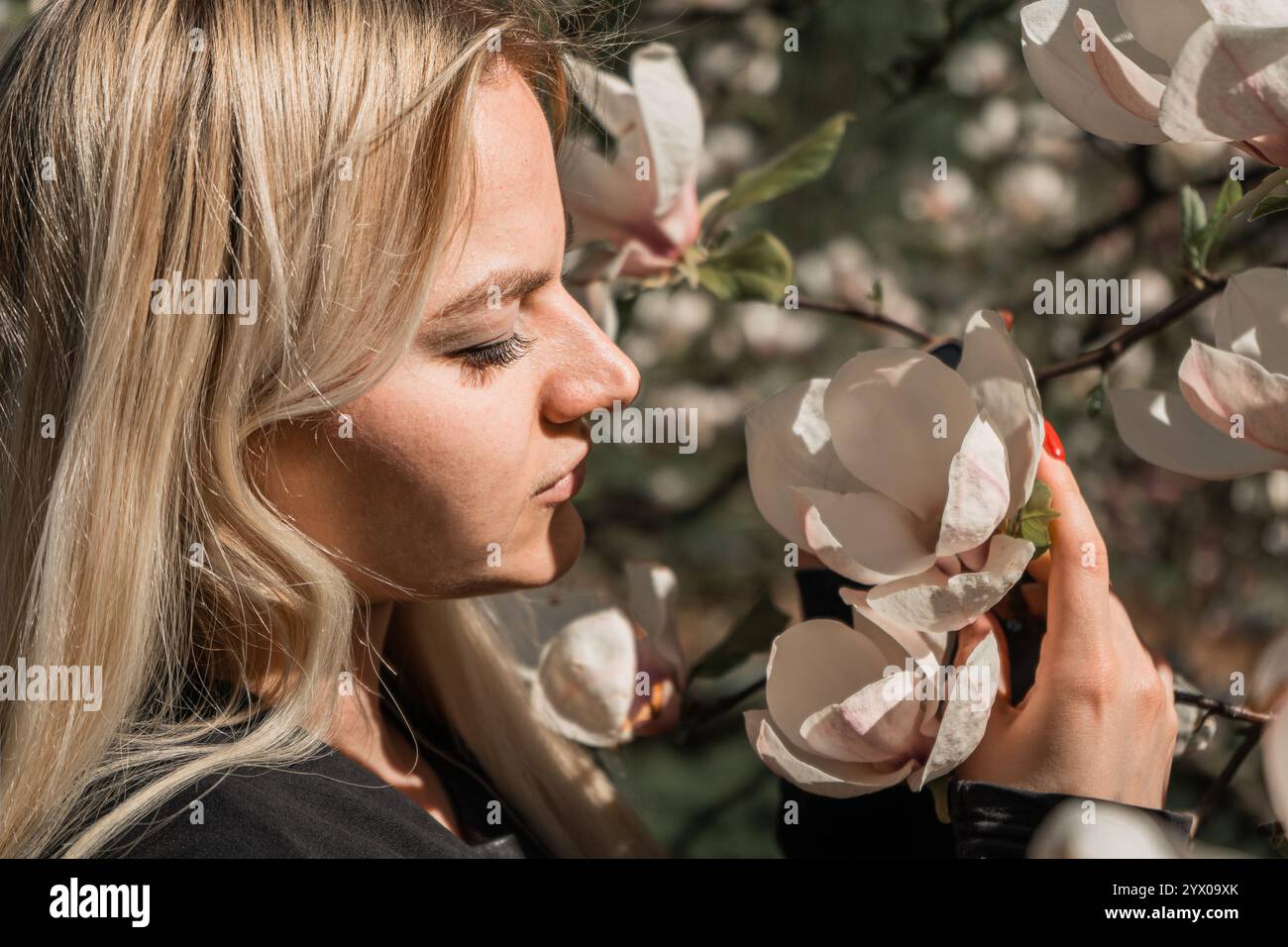 Stylish young woman posing outdoors surrounded by soft pink tones of ...