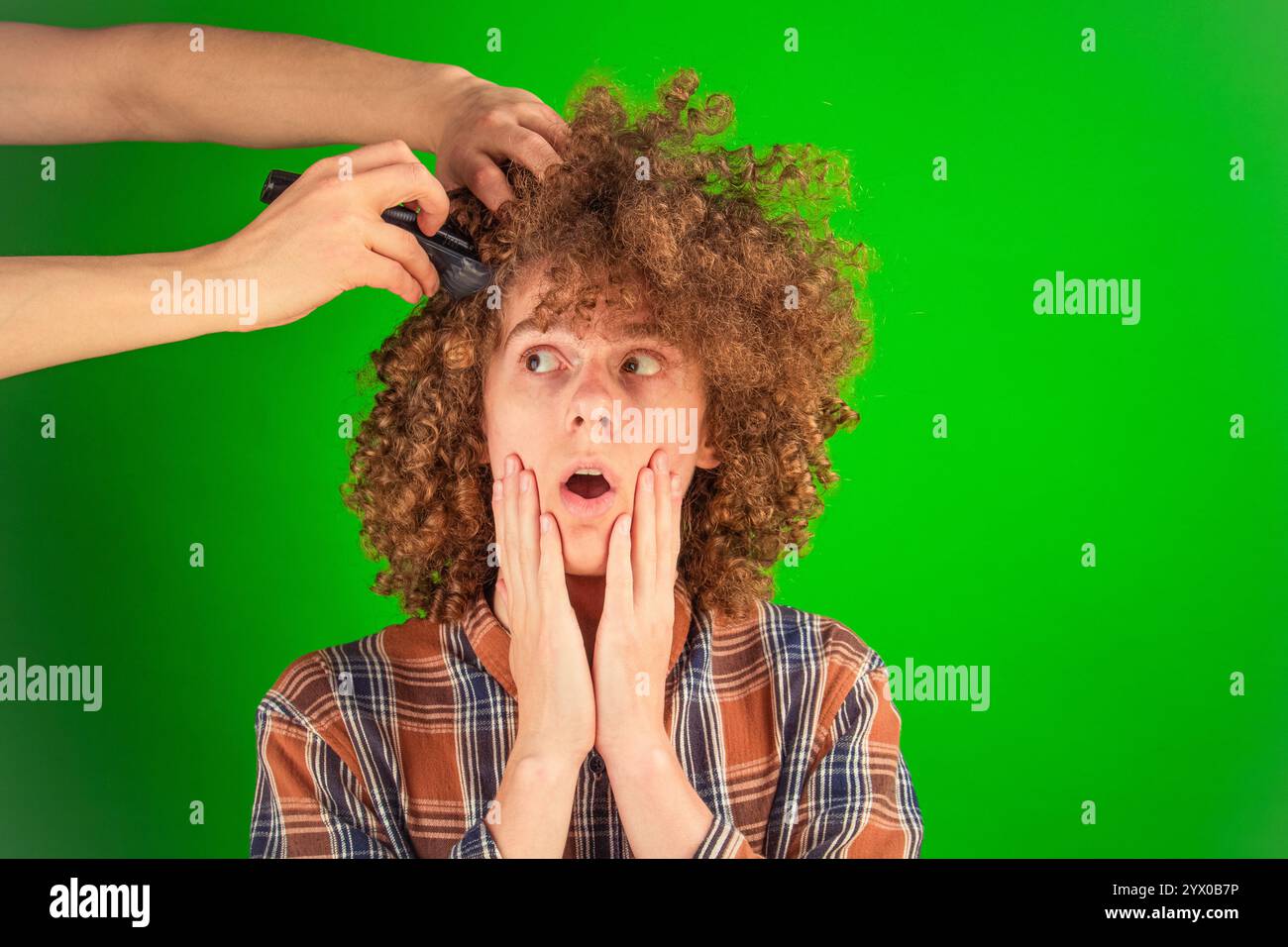 A boy with soft, curly hair sits still as a trimmer passes through his ...