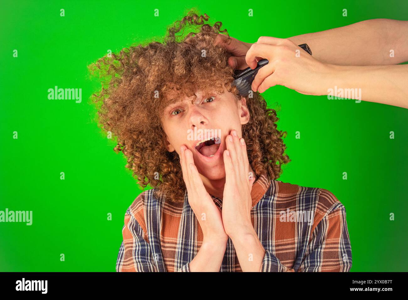 The curly-haired boy remains motionless as a trimmer glides through his ...