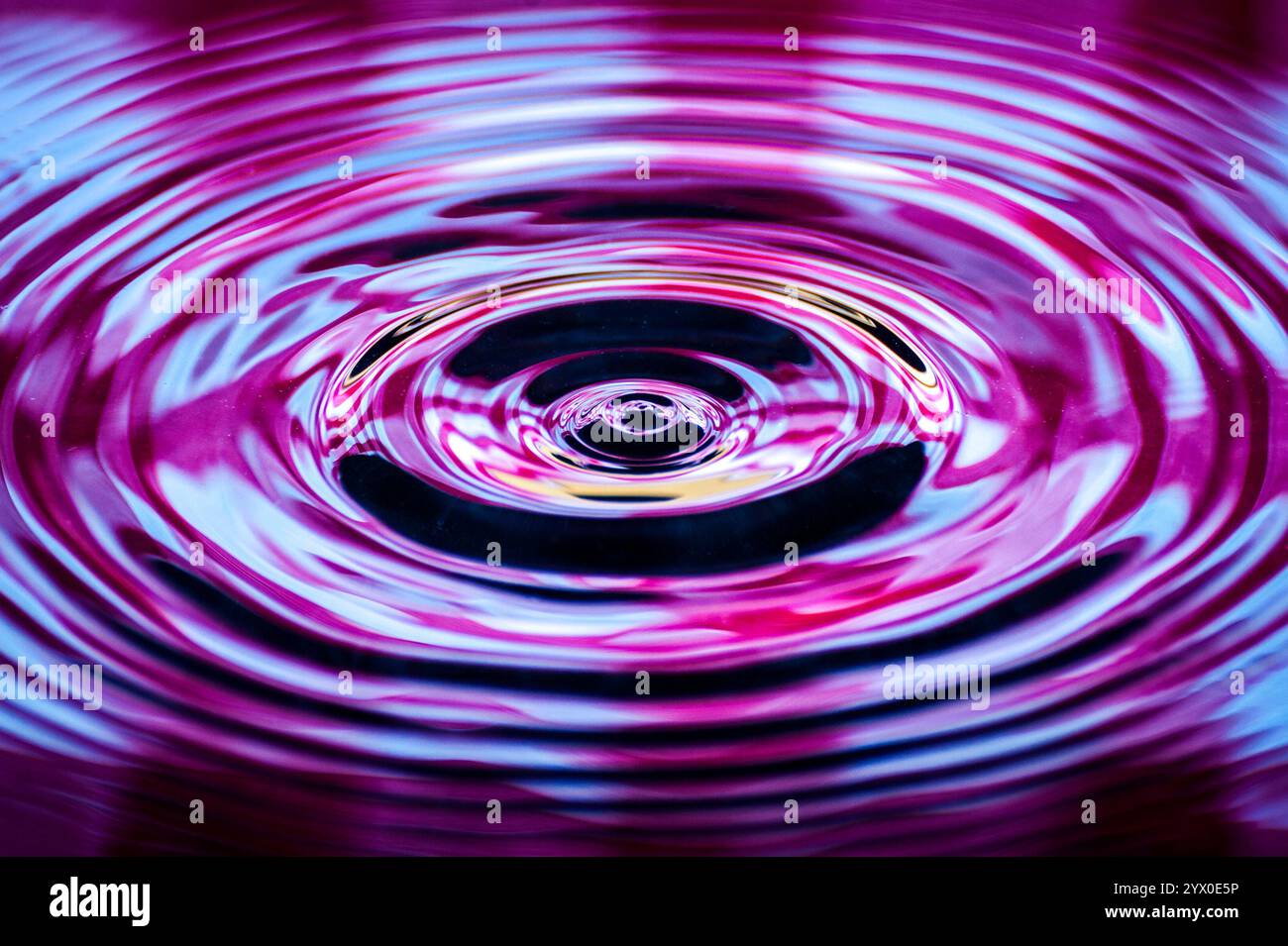 Waves of water caused by the falling droplets with psychedelic lighting ...