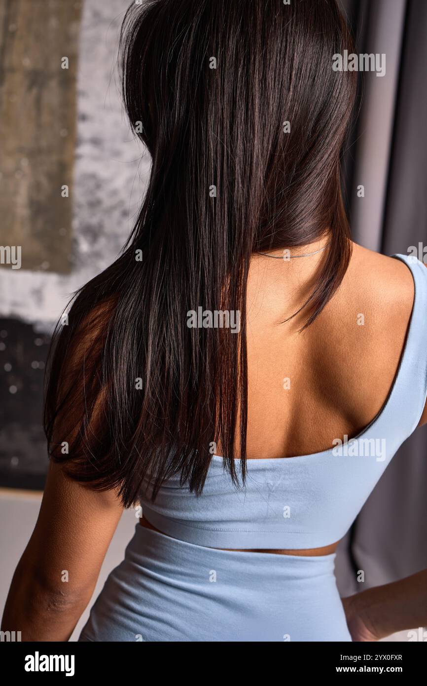 Chic woman in fashionable blue attire displaying sleek long hair and ...