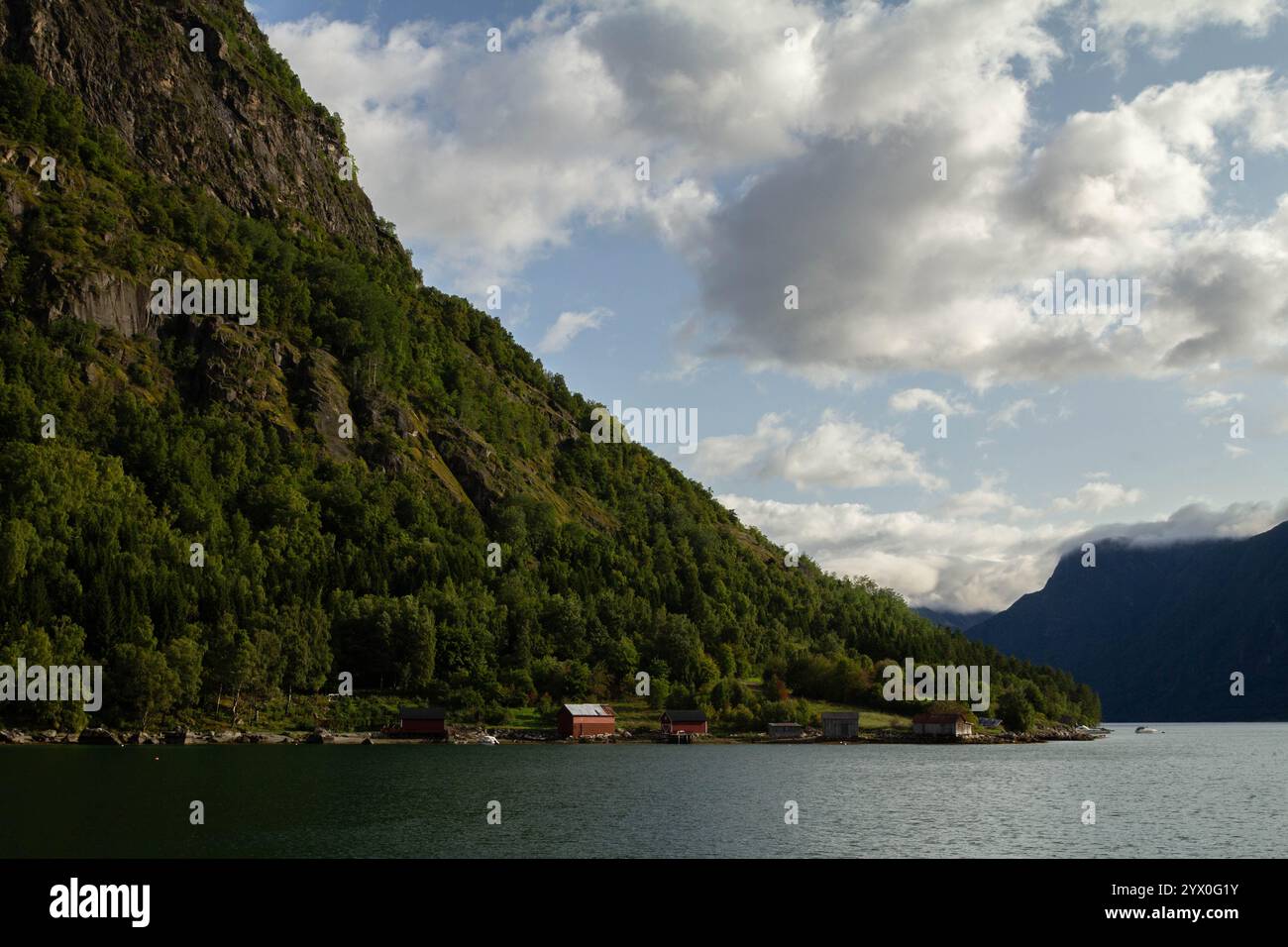 A stunning view of a mountain covered in lush forest, with a calm fjord ...