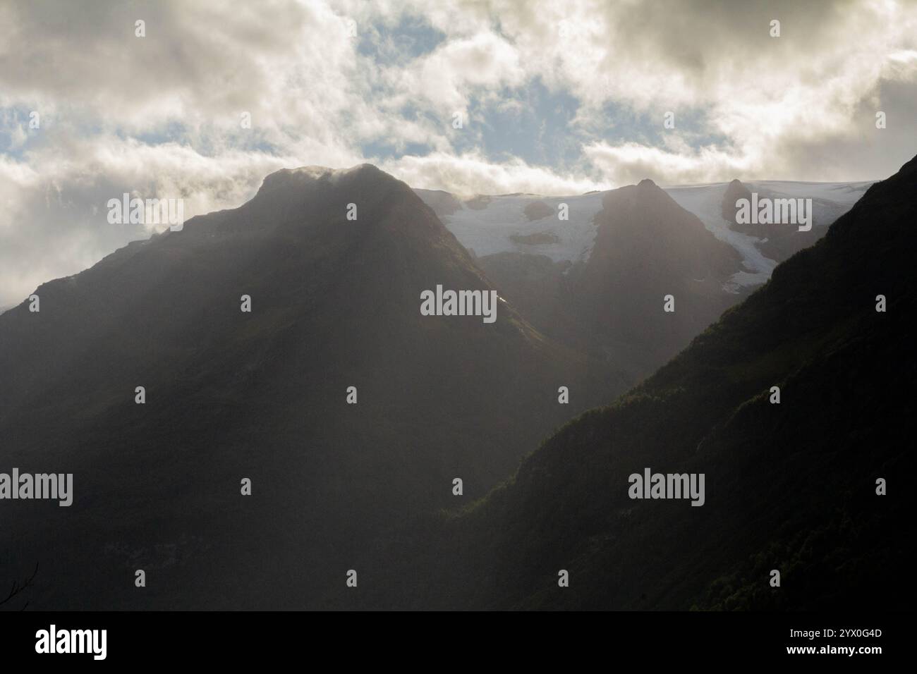 Beams of light pierce through the rugged mountains, illuminating the ...