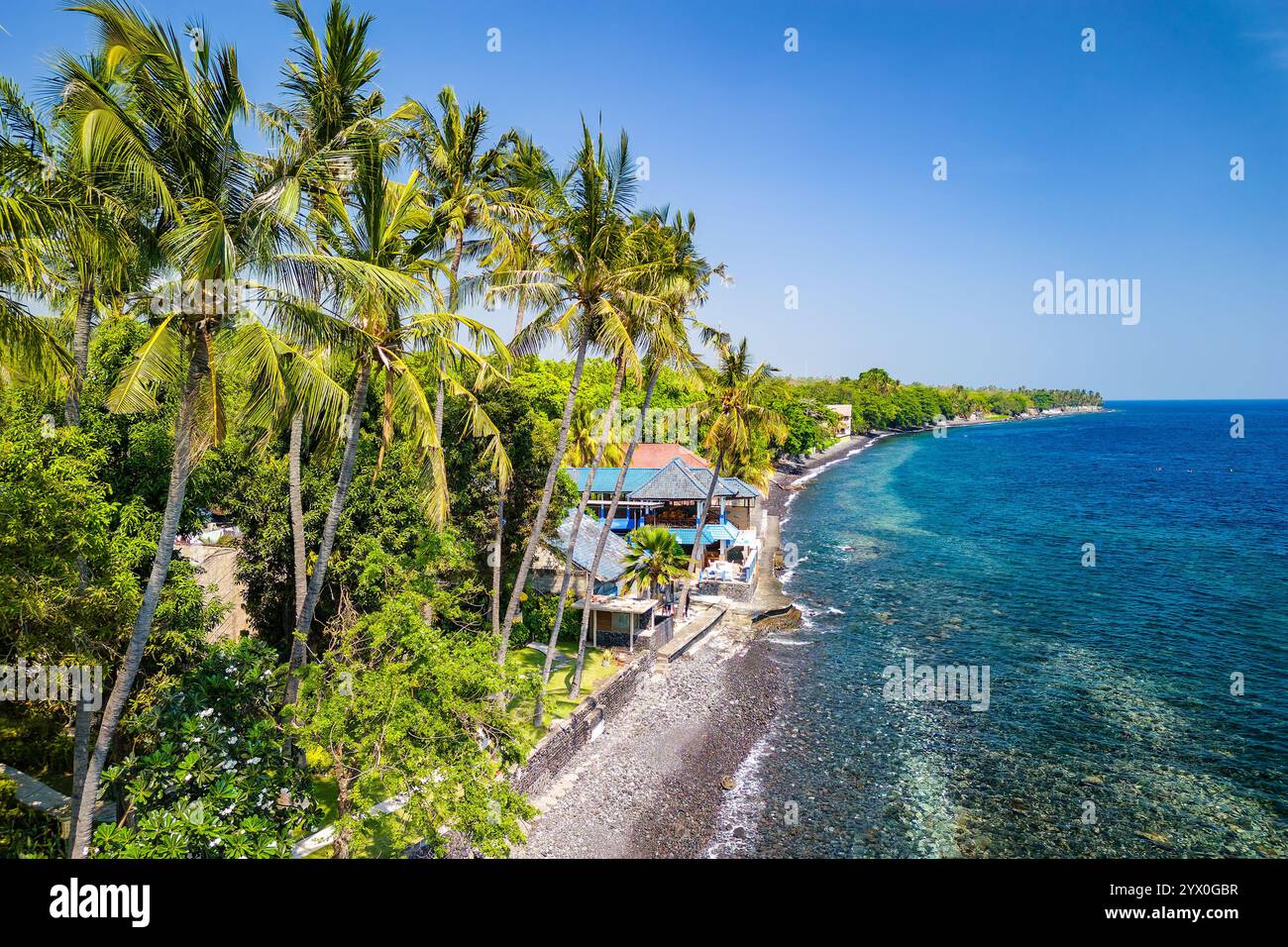 Elevated view of the volcanic beach and tropical vegetation of the village of Tulamben, Bali ...