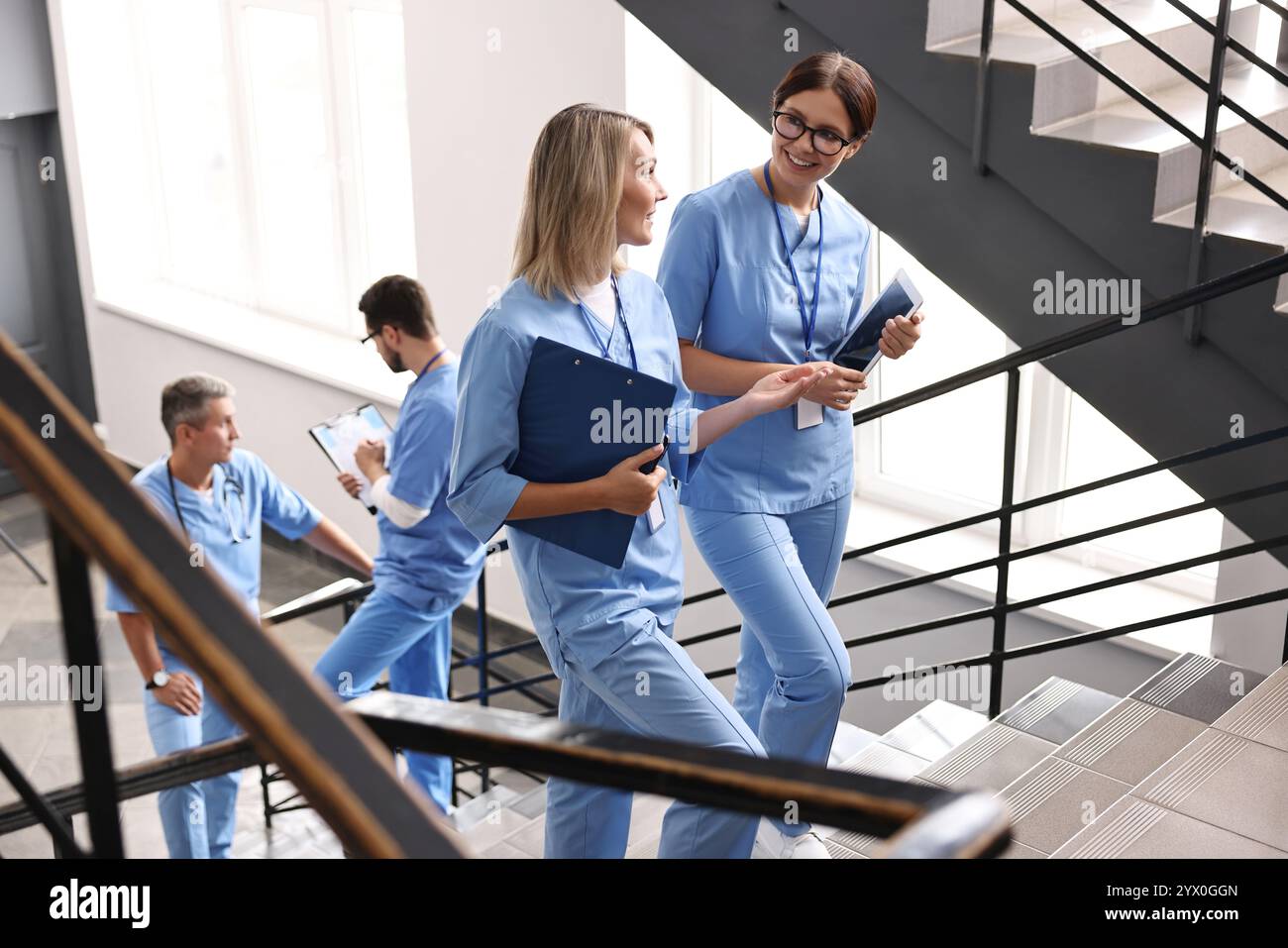 Healthcare workers with tablet and clipboard walking up stairs in ...