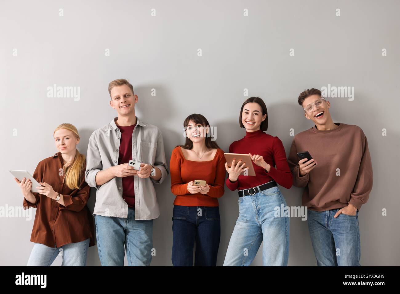 Group of people using different gadgets near light grey wall indoors ...