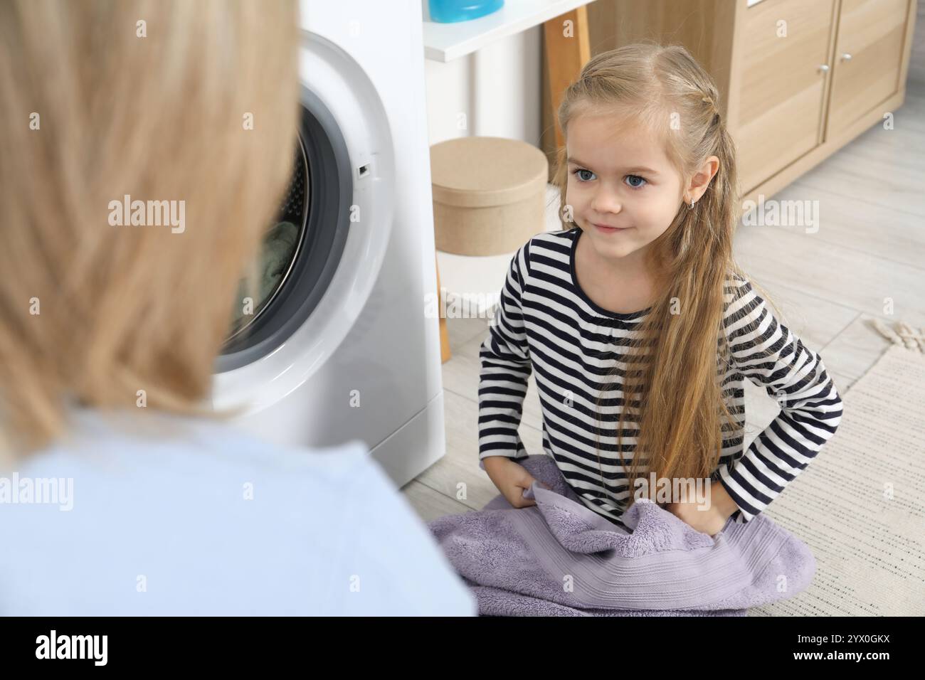 Little girl helping her mom doing laundry at home Stock Photo - Alamy
