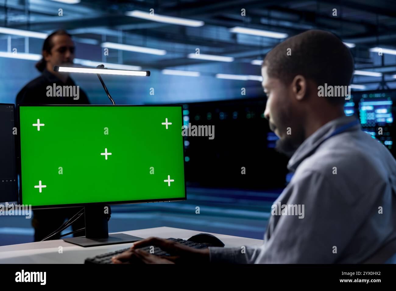 Employee using green screen PC to check for signs of imminent failure in data center ...