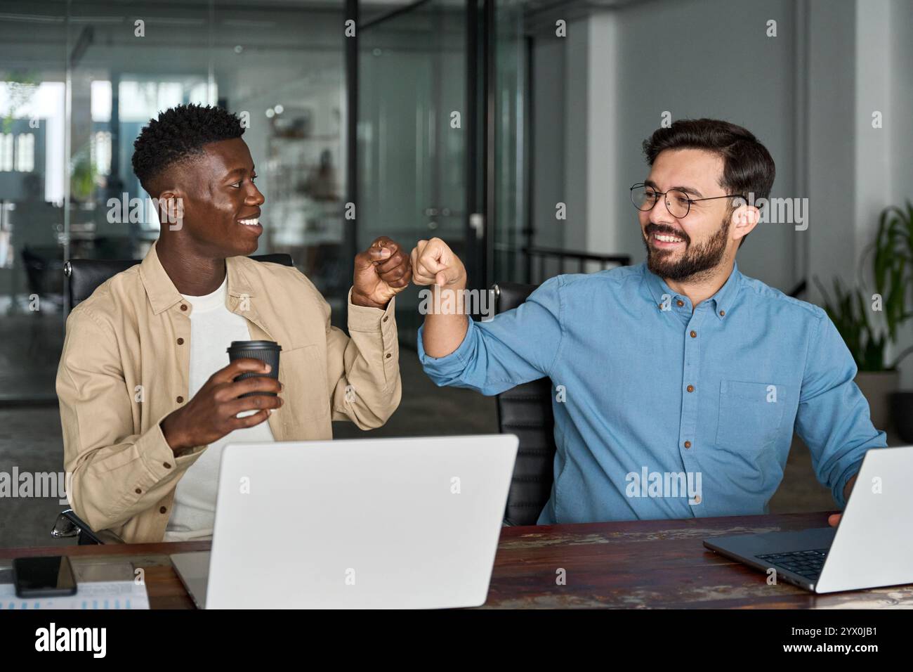 Two happy diverse professional male employees team giving fist bump at ...
