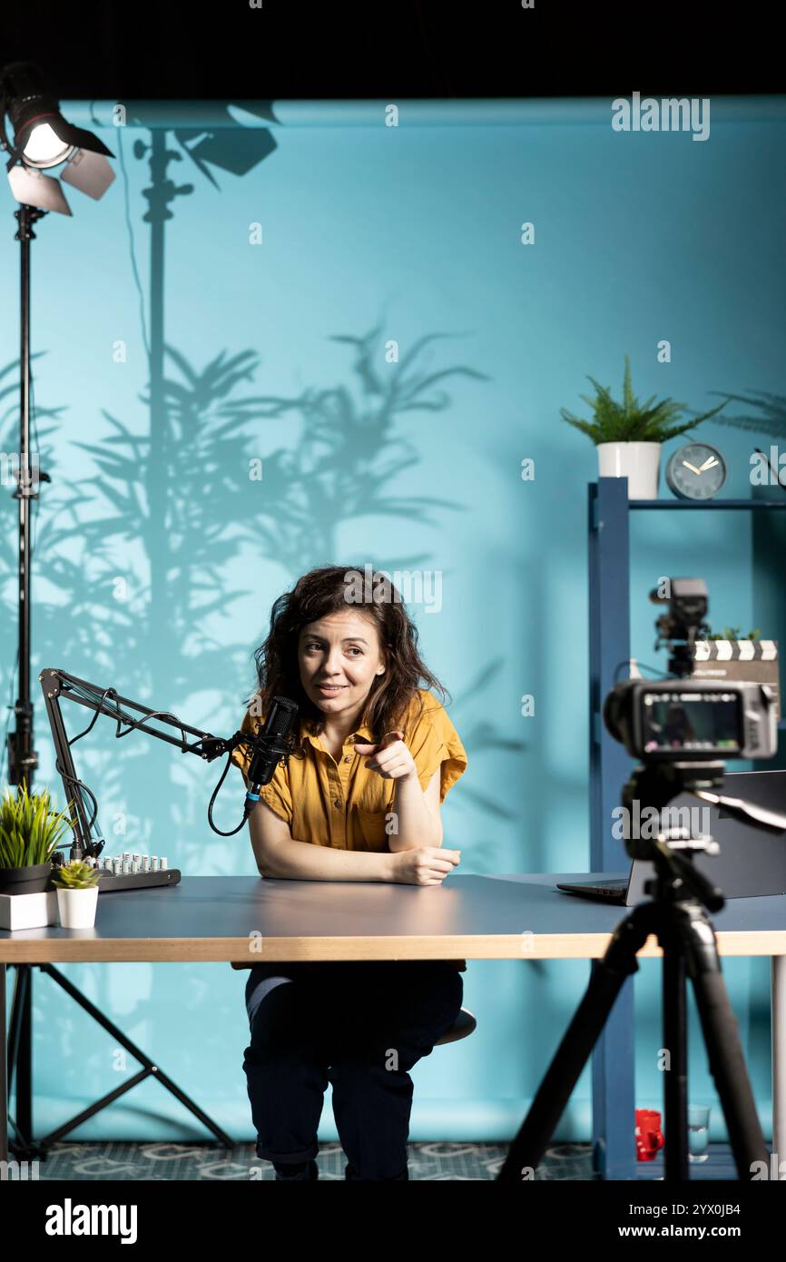 Jolly woman filming vlog pointing finger to high tech camera in ...