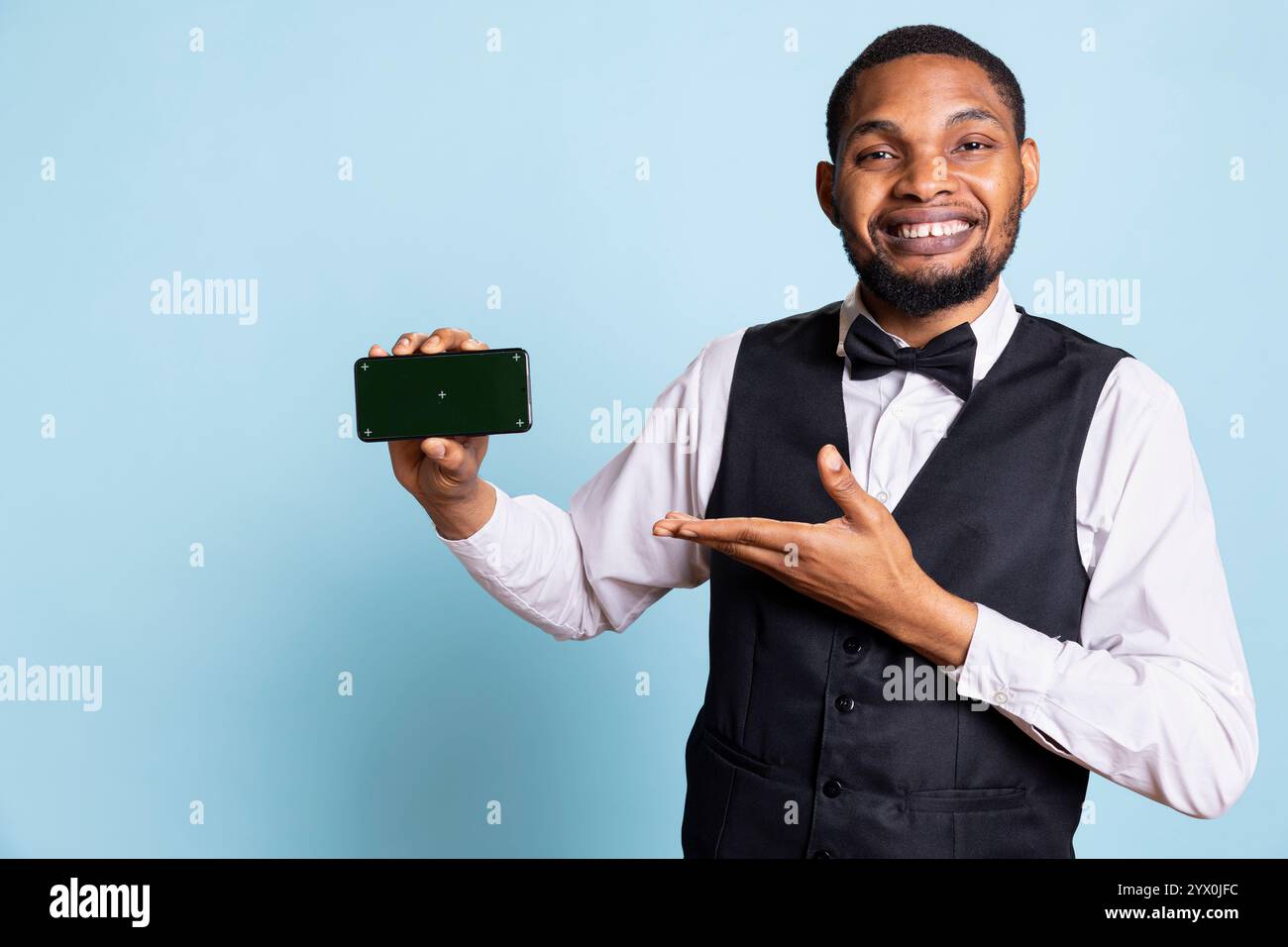 Hotel porter in tuxedo showing copy space mockup on a smartphone ...