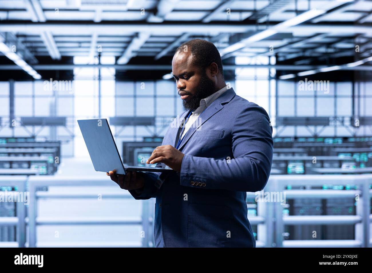 IT staff member in server hub using laptop to monitor energy consumption across supercomputer ...