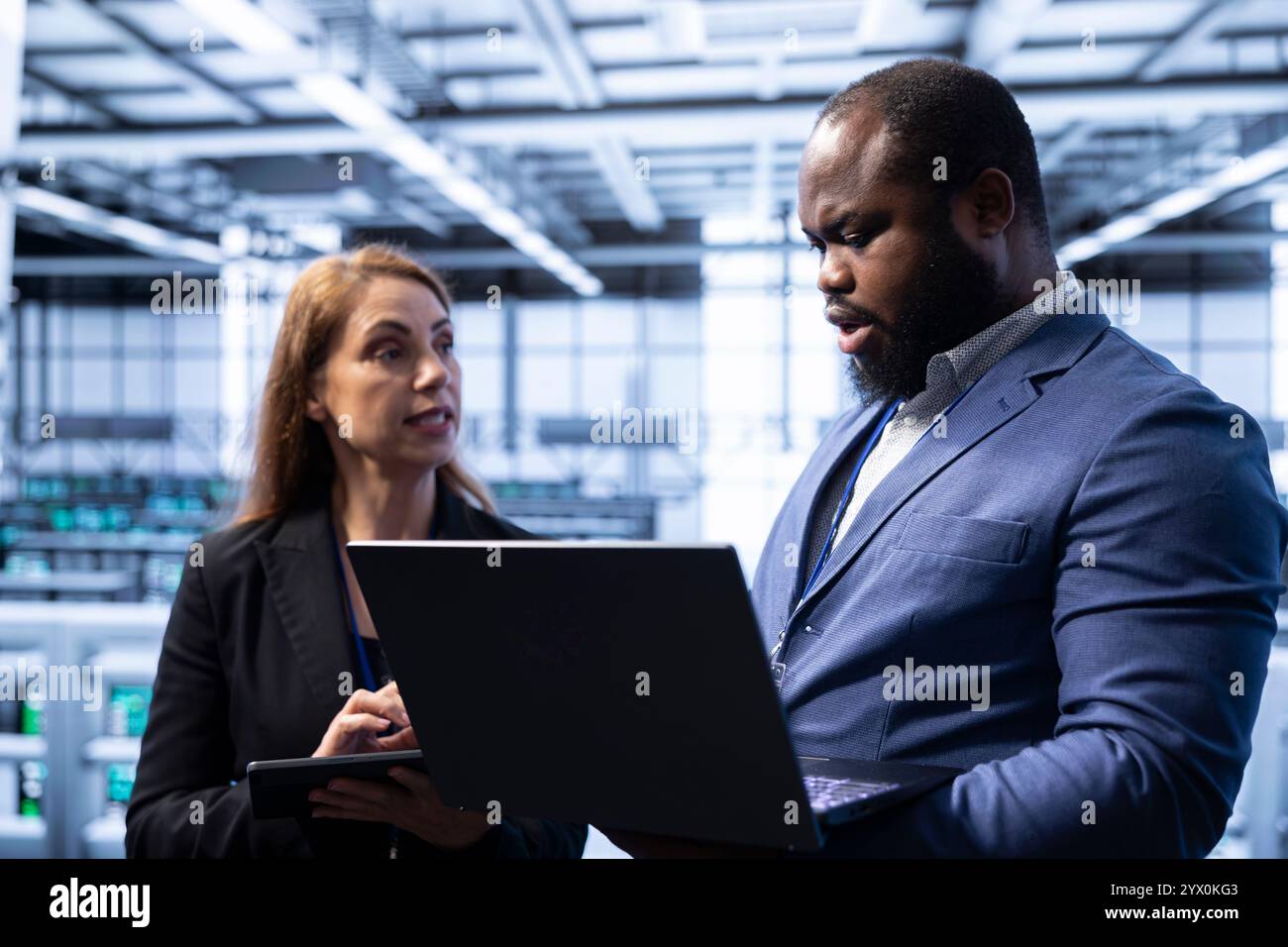 Employee in server hub showing manager recovery plan on laptop ...
