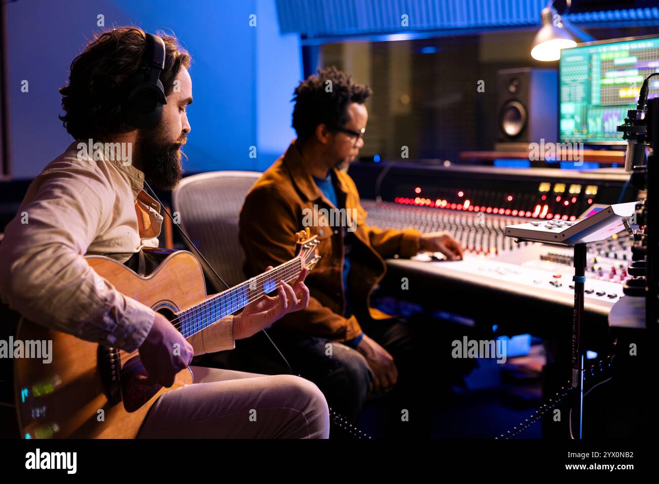 Singer playing a new hit song on his guitar in control room, recording ...