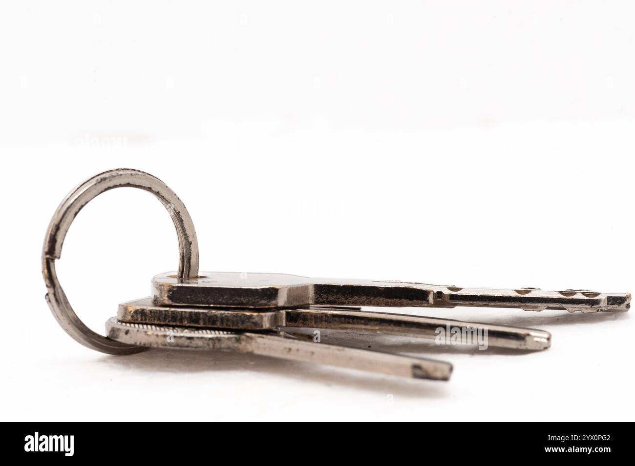 Three keys are hanging from a key chain. The keys are silver and have a ...