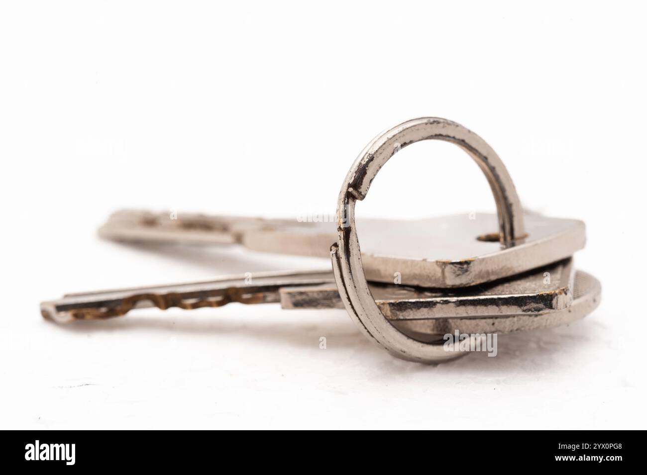 Three keys are hanging from a key chain. The keys are silver and have a ...