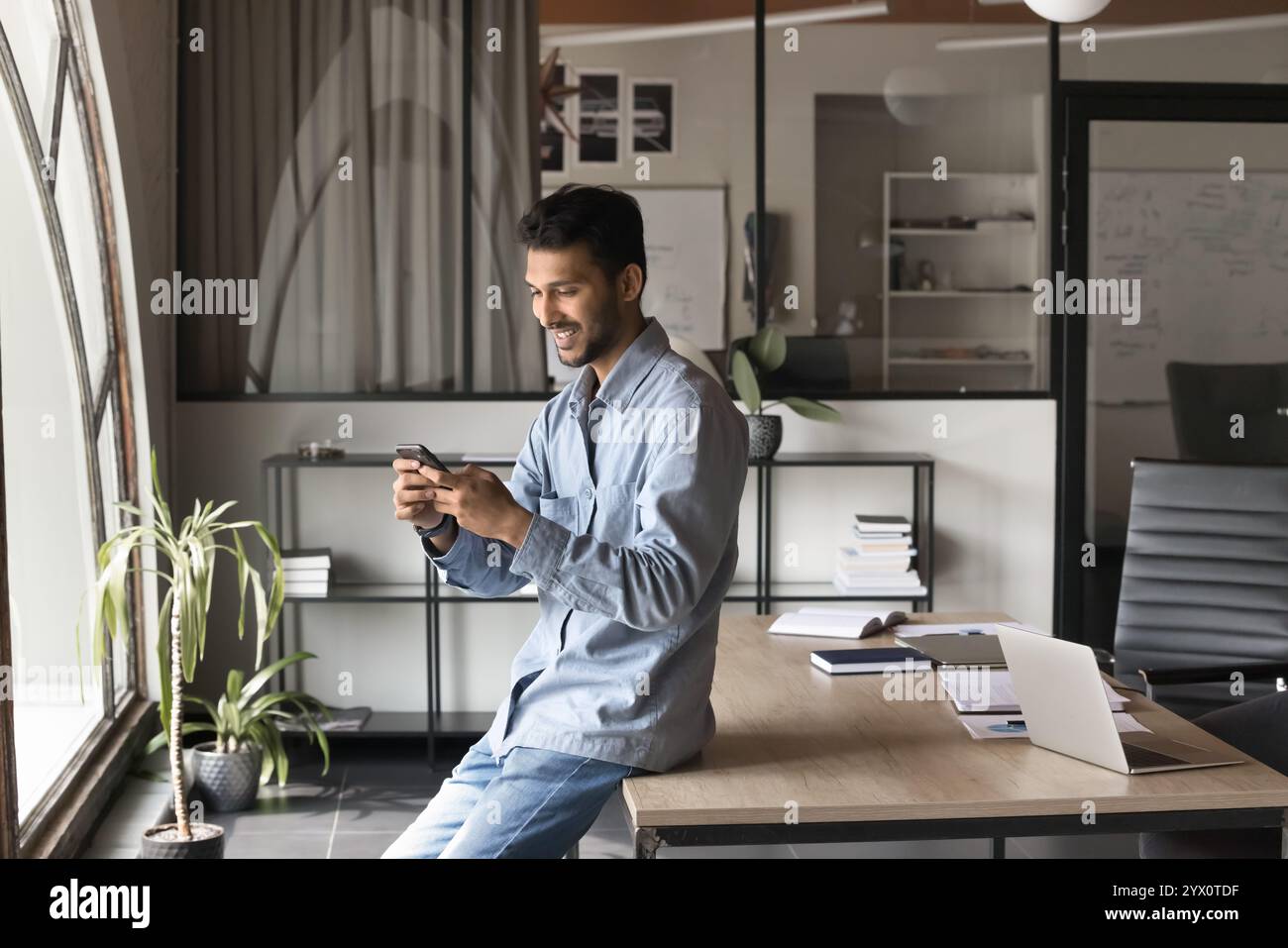 Smiling Indian male office employee using his smartphone during break Stock Photo - Alamy