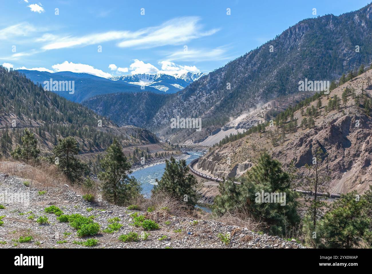 Cargo train moves slowly along the Fraser River in Fraser Canyon near ...