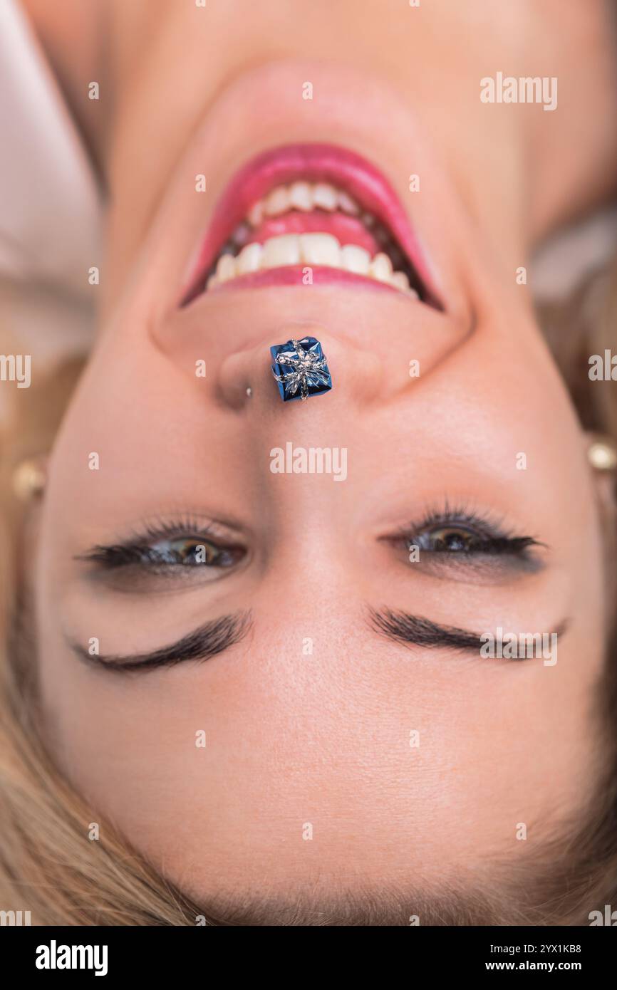 Close-up portrait capturing a cheerful young woman lying upside down ...