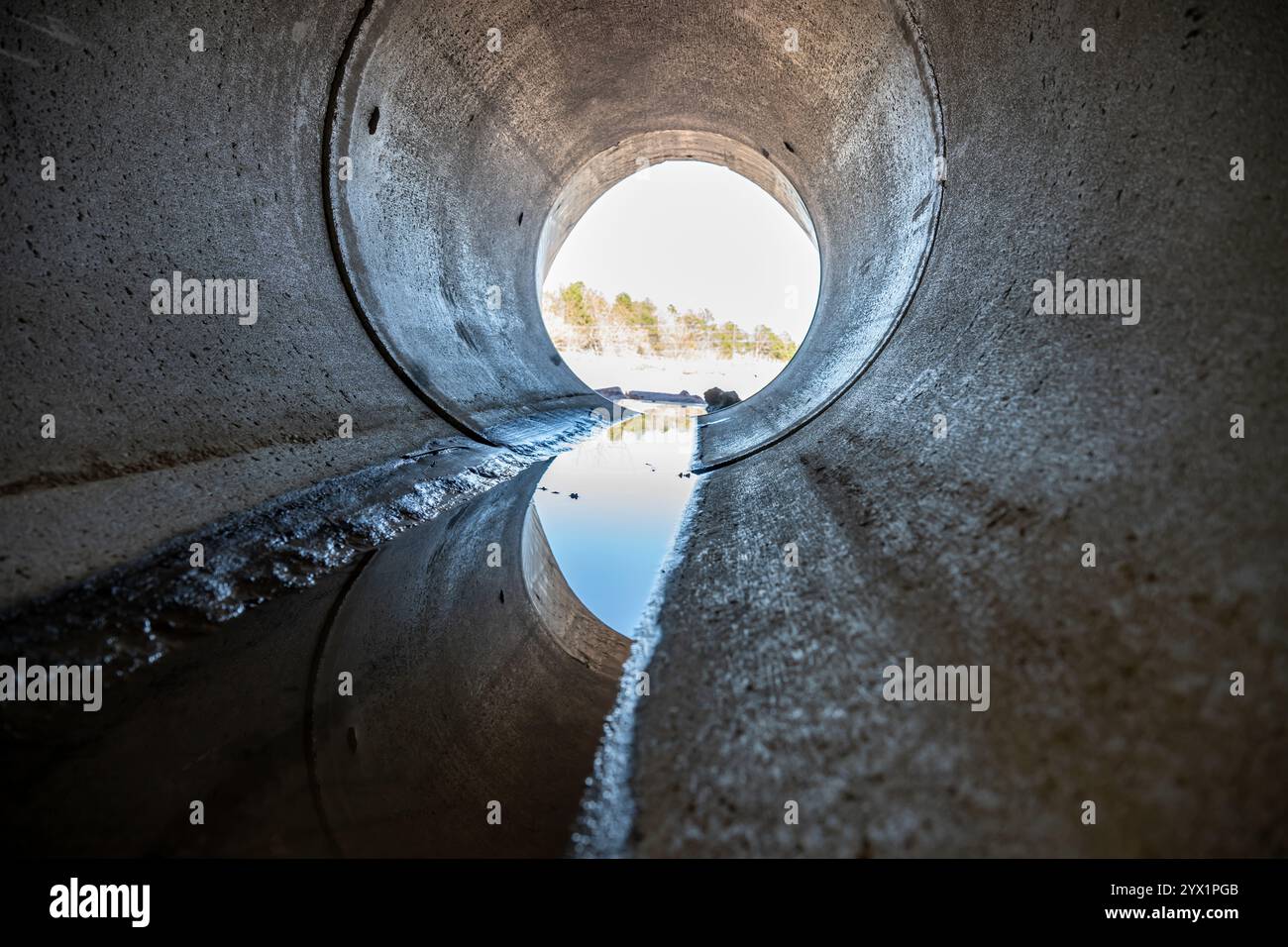 Inside a circular concrete drainage culvert with a trickle of water ...