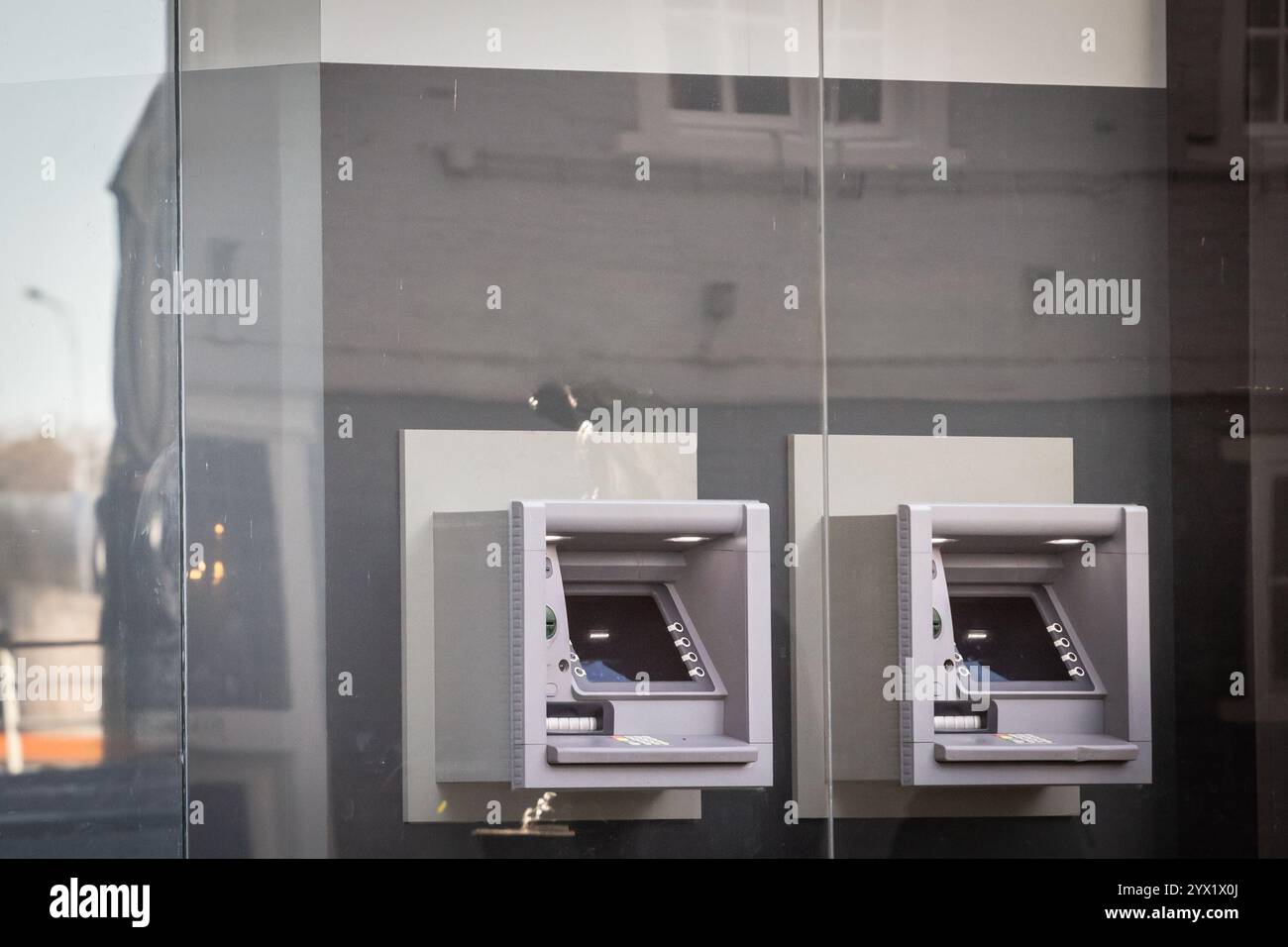 Two modern ATMs are installed side-by-side on a glass façade in the ...