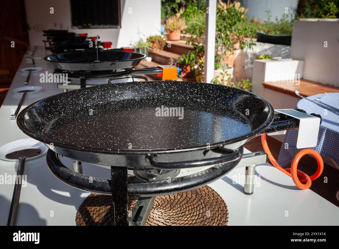 A paellera rests atop a gas burner, awaiting fresh ingredients. This ...