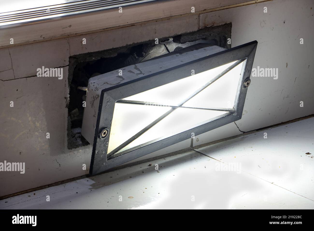 A damaged light shines under a step of the stairs Stock Photo - Alamy