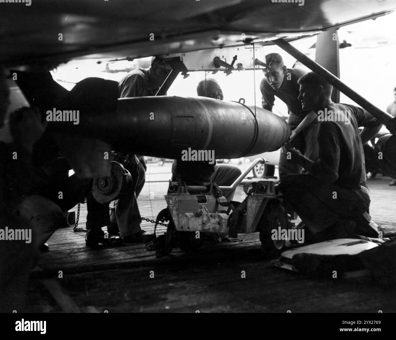 Crewmen aboard USS Ranger (CVA-61) load a bomb on a Douglas A-1H ...