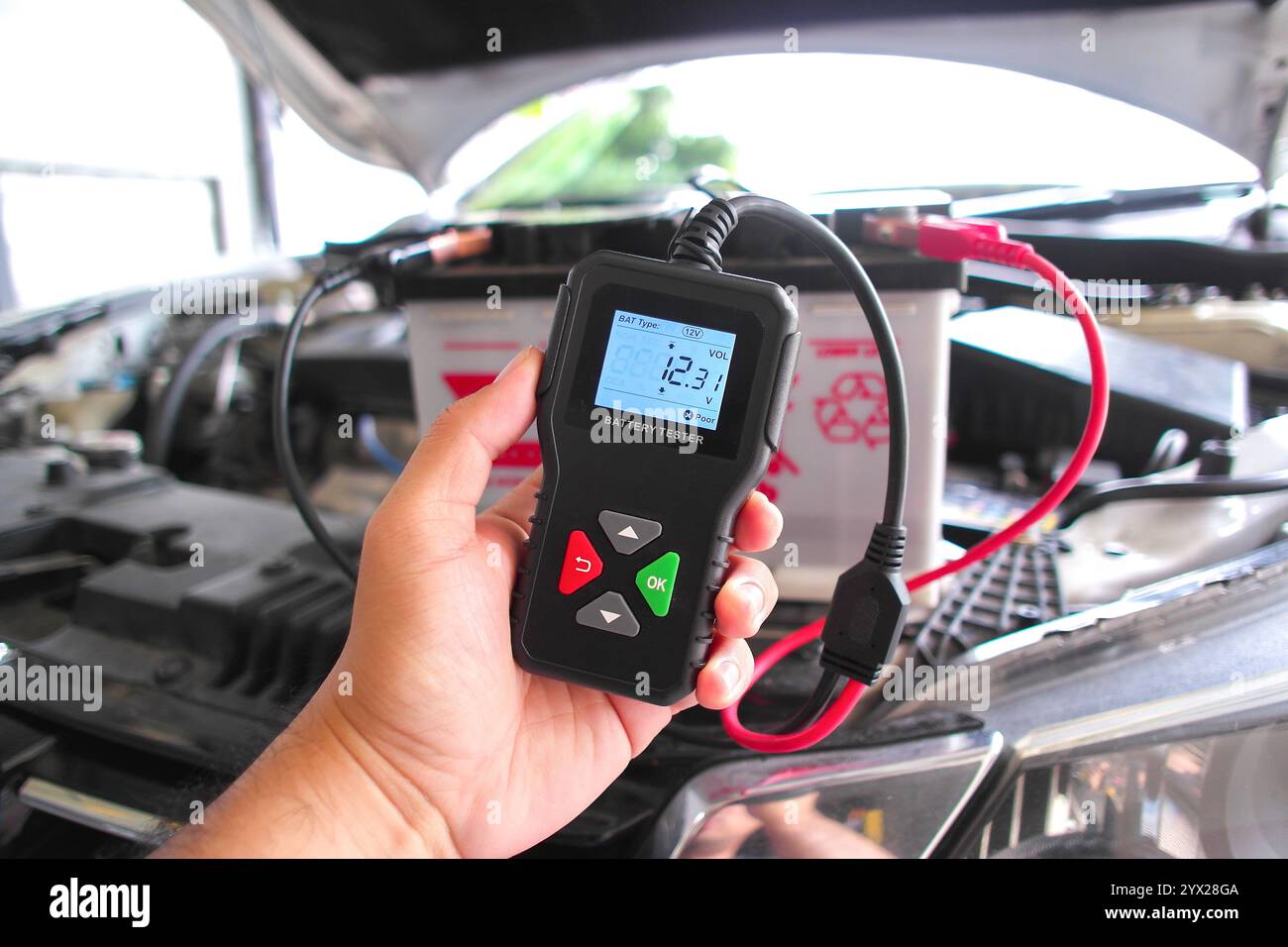 Car battery voltage tester in use under the hood of car by auto ...