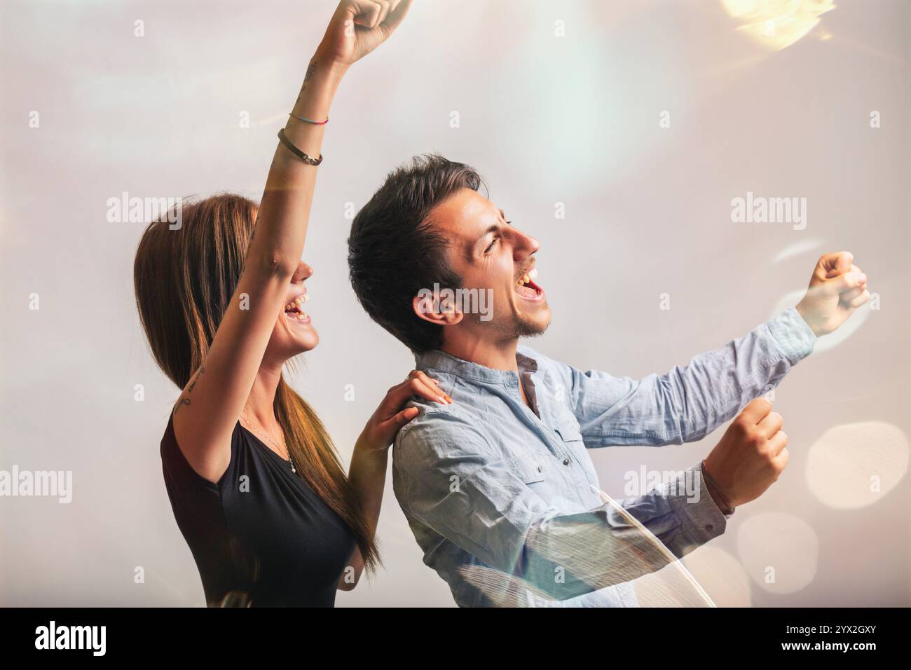 Young couple celebrating together, raising their arms in joyful triumph ...