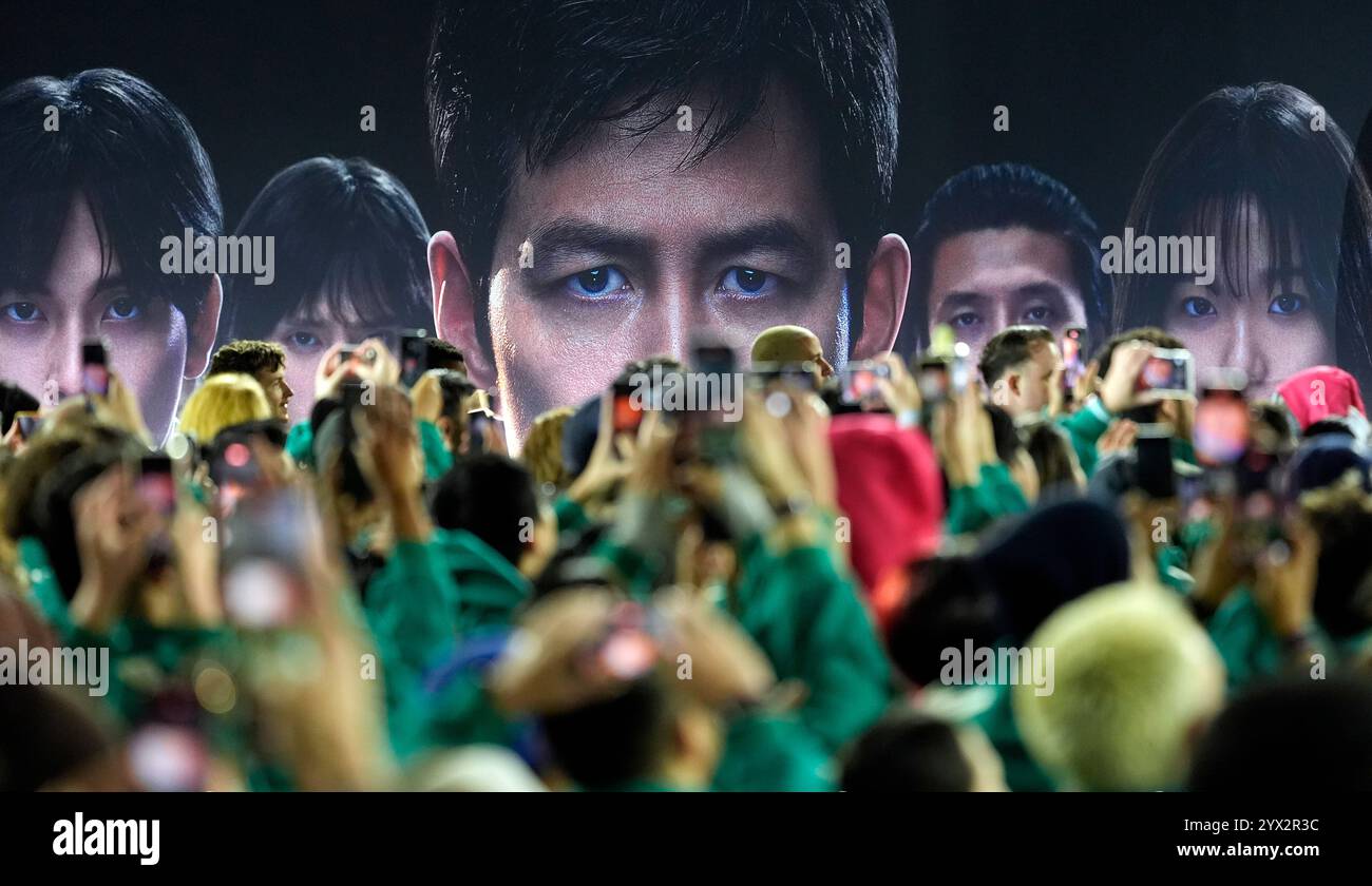 A large image of cast members of "Squid Game" loom over the crowd at ...