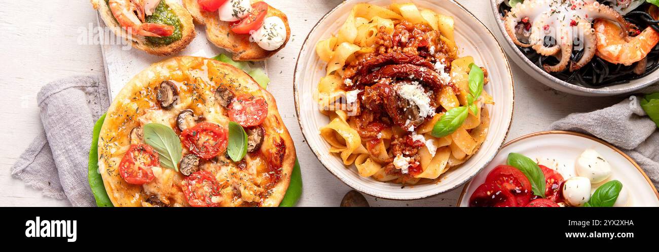 Full table of italian meals on plates Pizza, pasta, ravioli, caprese ...