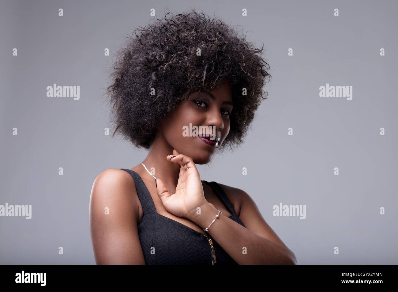 Stylish young woman with a voluminous afro hairstyle is posing ...