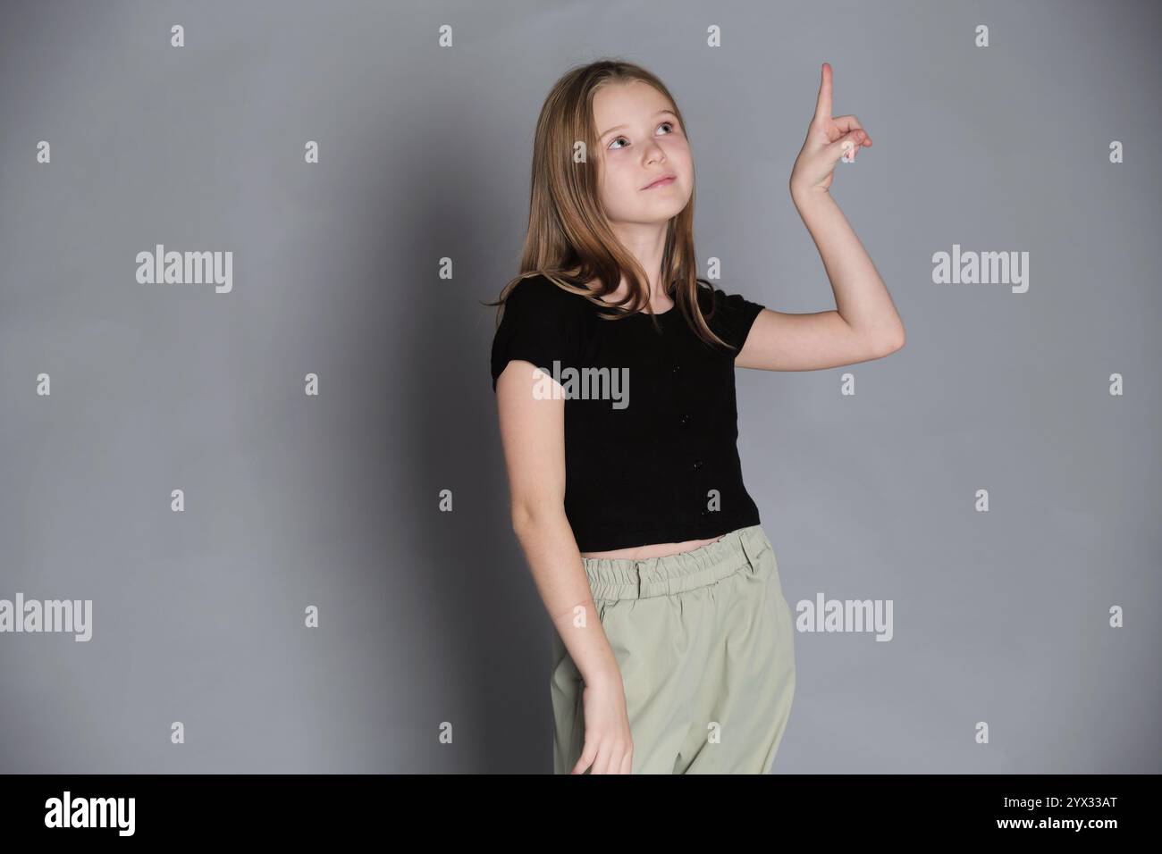 A girl presents an invisible object, her gaze confident. Represents the ...