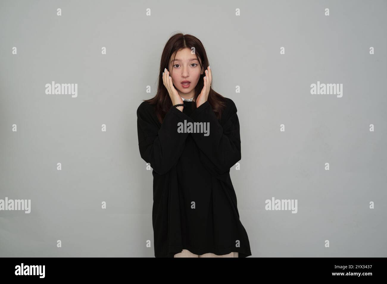 Startled female in black, hands on cheeks, mouth open. Reflects the ...