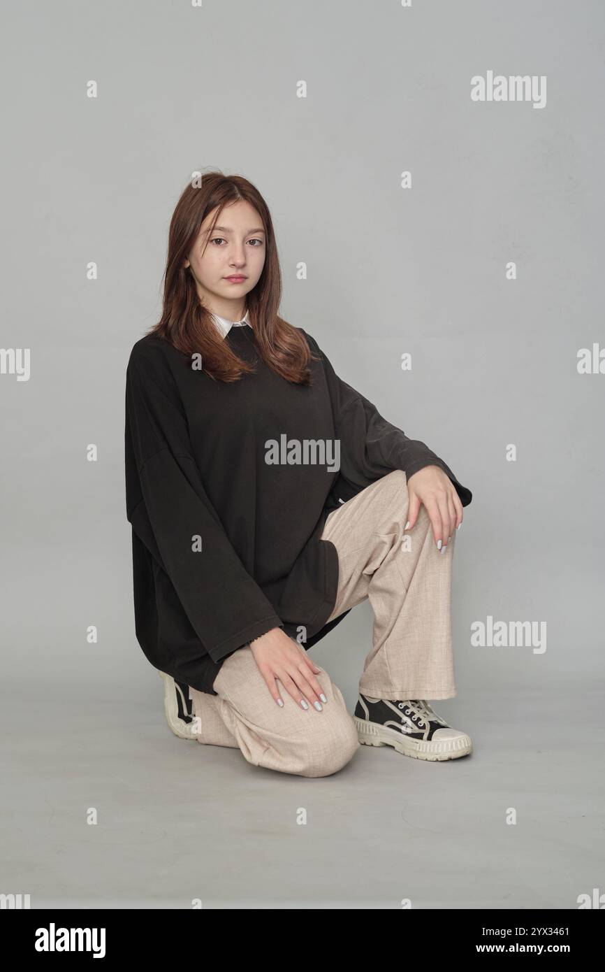Casually stylish young woman sitting, displaying a mix of modern and ...