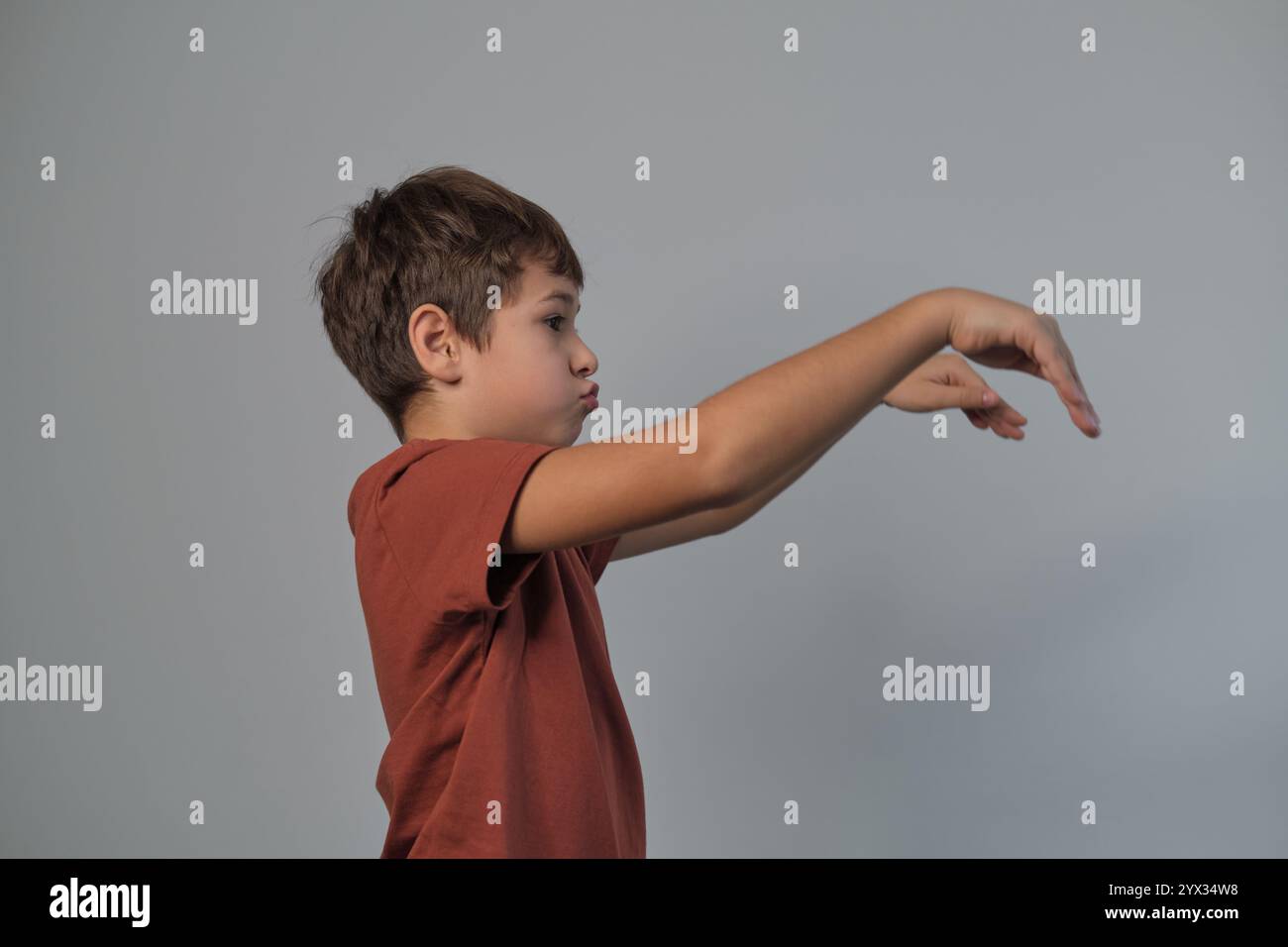 A boy playfully stretches his arms forward with dramatic gestures ...