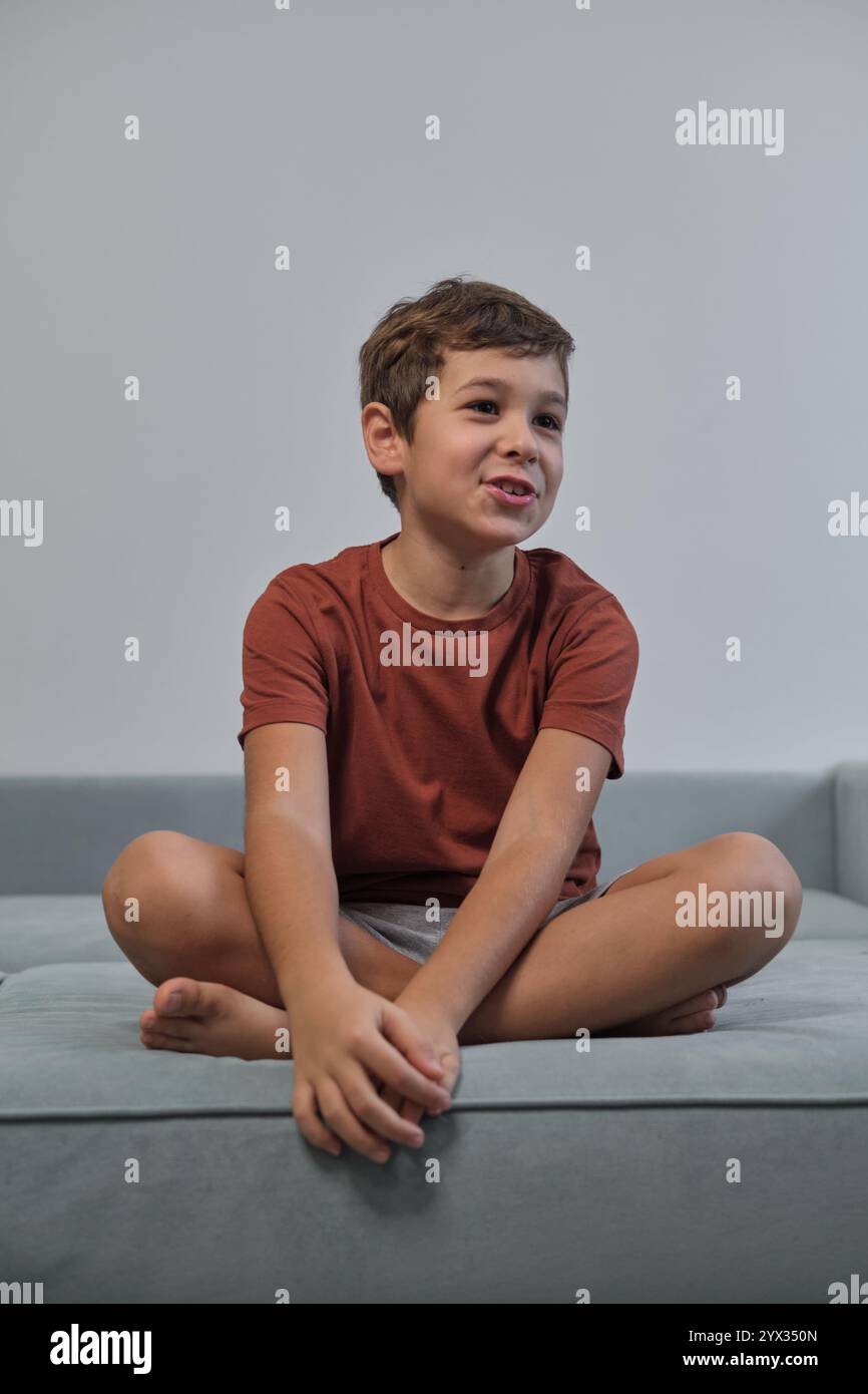 A boy sits, cross-legged, tongue out in jest. His playful pose counters ...