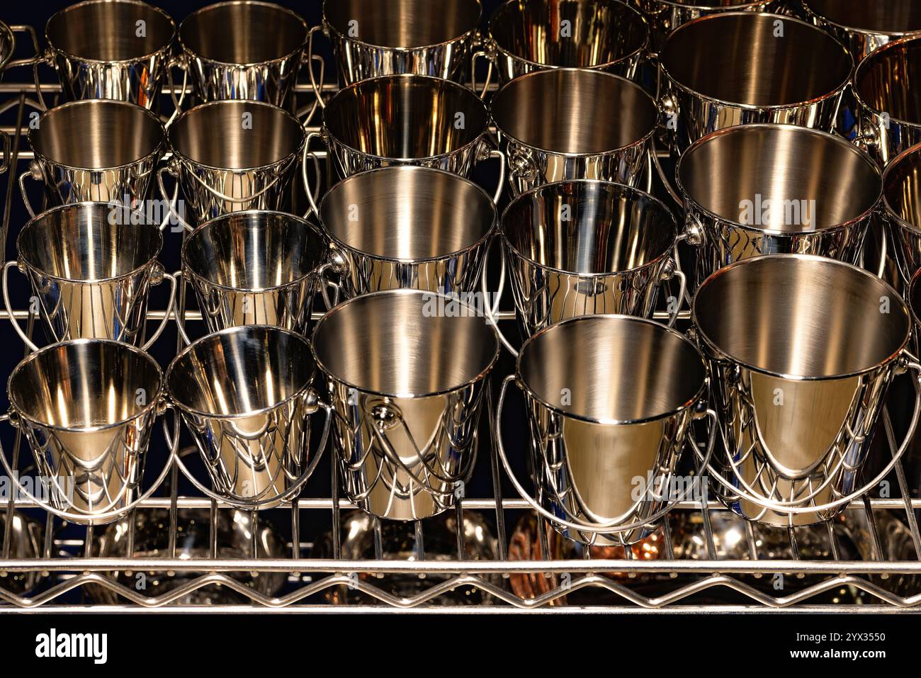 Unique collection of polished metal cups arranged on a silver rack in a ...