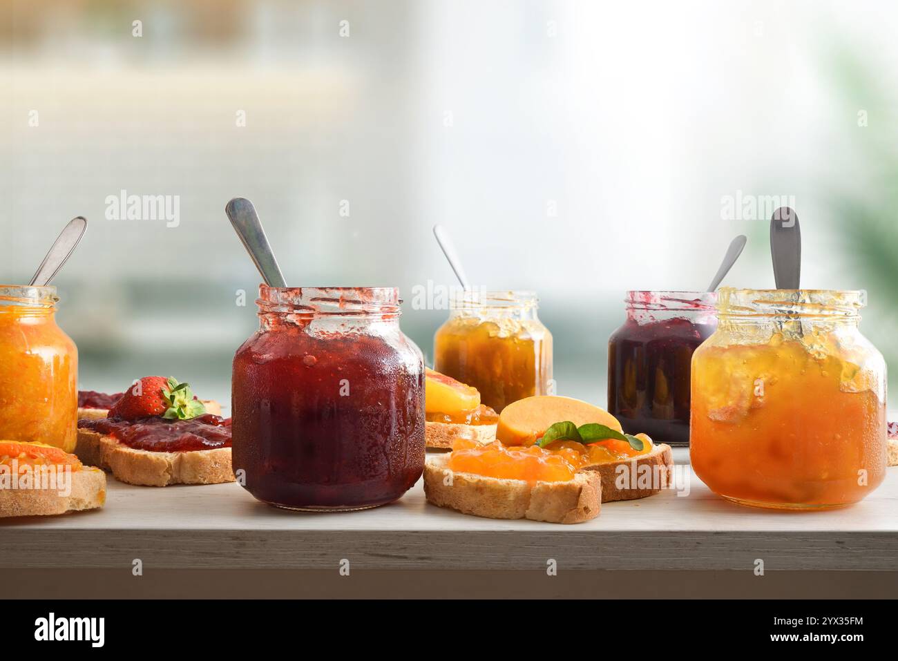 Jars full of jam of various flavors and slices of bread with jam ...