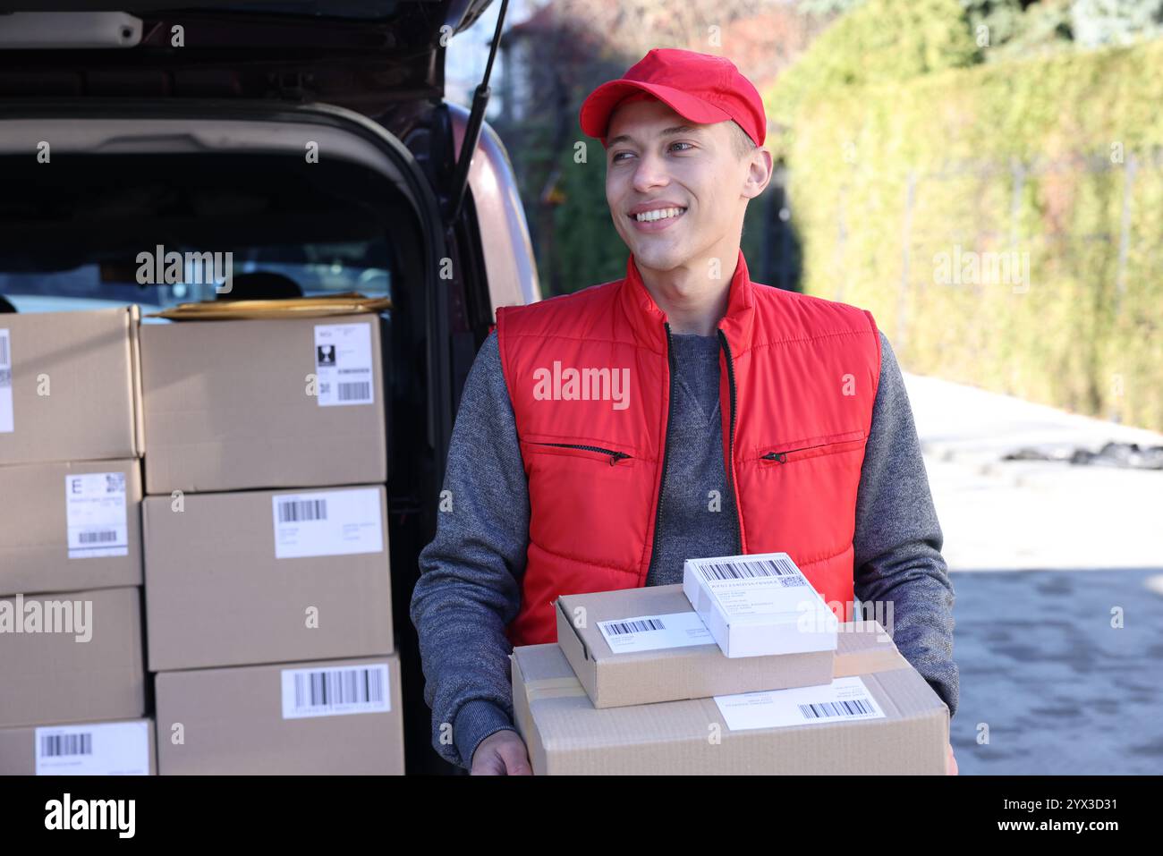 Happy postman with parcels near car outdoors Stock Photo - Alamy