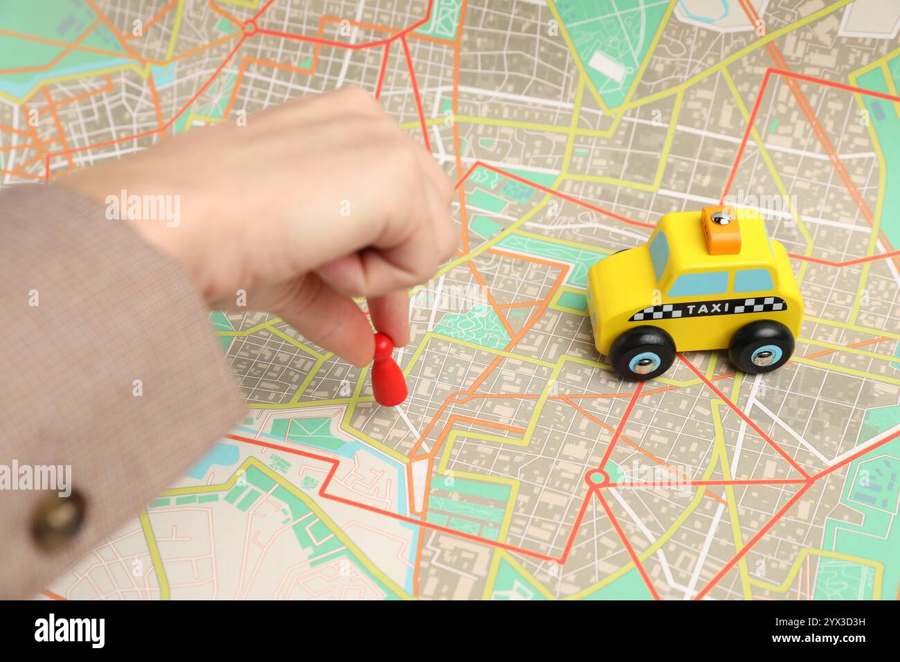 Woman putting red human figure on city map near toy taxi car, closeup ...
