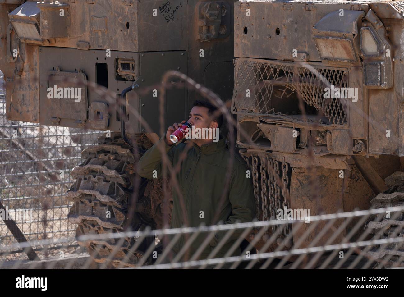 An Israeli soldier drinks a Coca-Cola Zero next to armoured vehicle ...