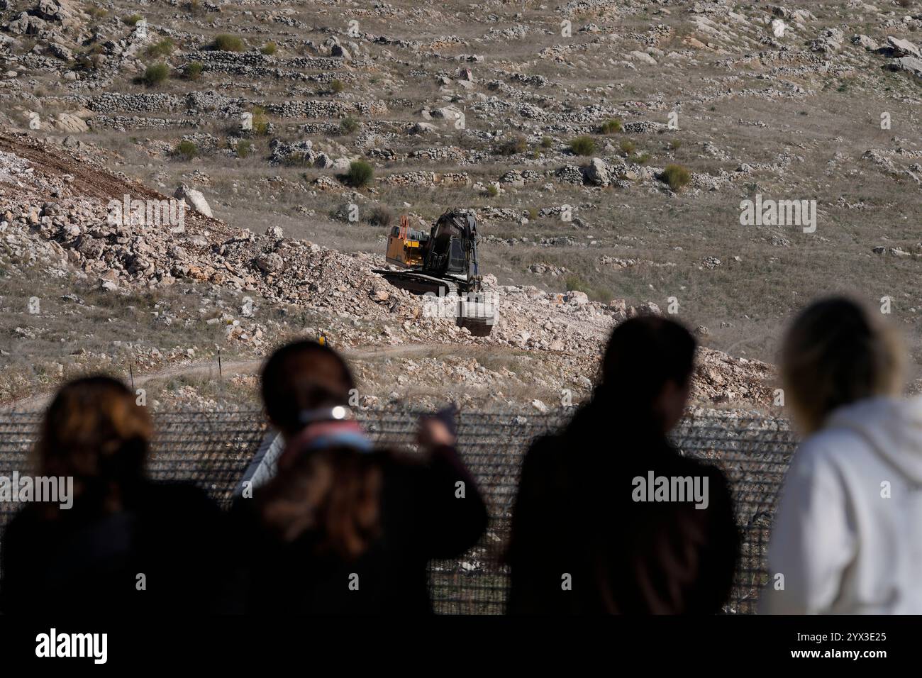 Locals stand along the security fence as they watch an Israeli ...