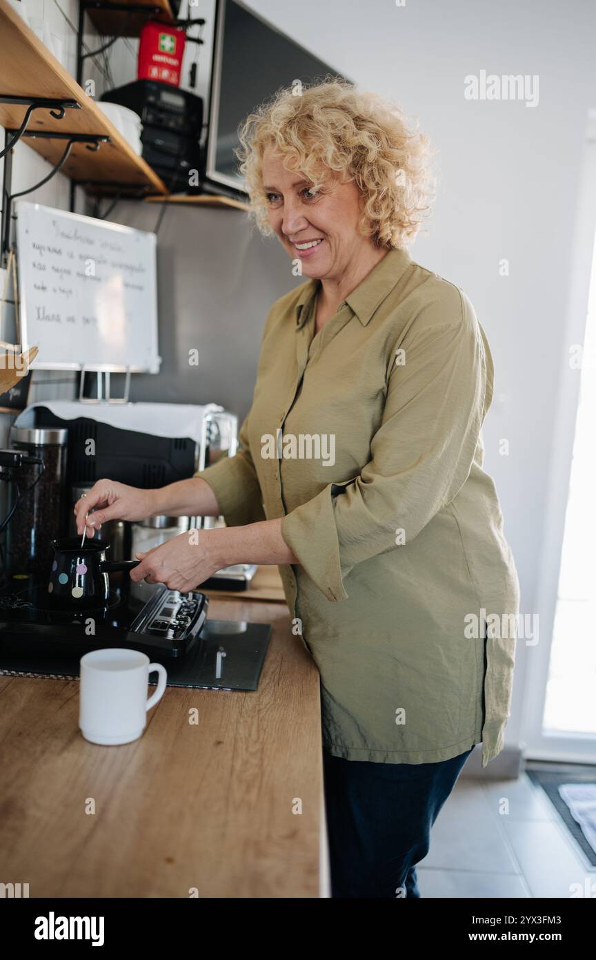 Happy mature woman making coffee in kitchen Stock Photo - Alamy