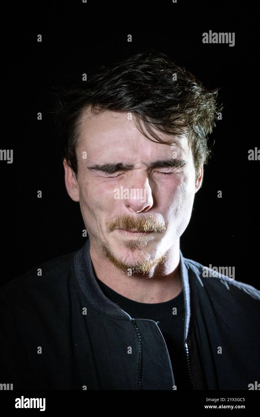 Studio portrait of a young ma with a strange emotion akin to madness or ...